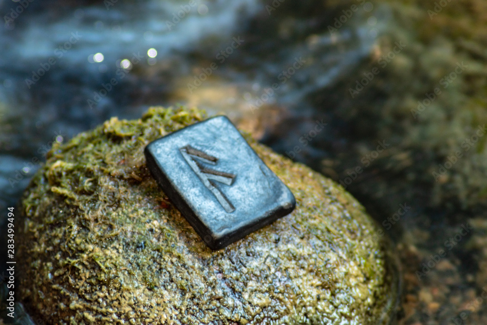 Norse rune Ansuz on the stone and the evening river background. The ...