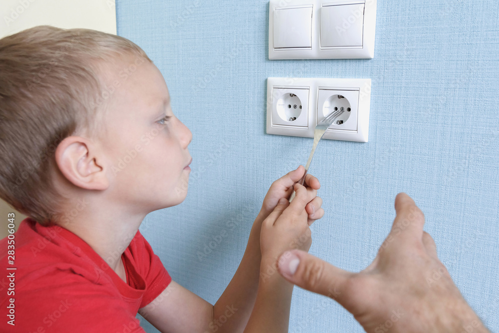 A father is trying to stop a child reaching for an electrical outlet ...