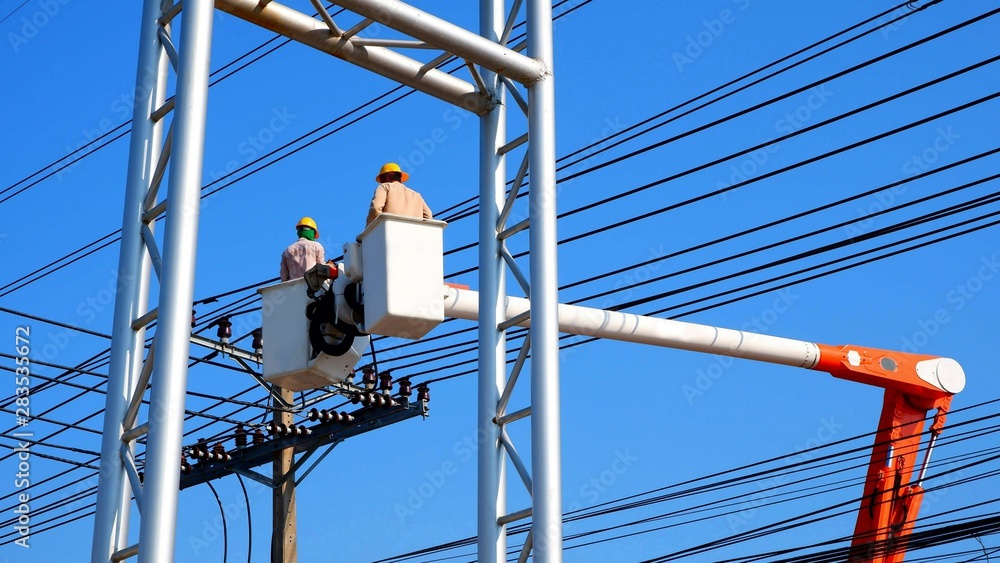 Low angle view of two electricians on electric cable car are working to ...
