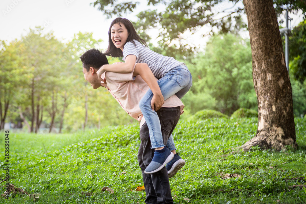 Foto de Happy asian father laugh giving piggyback ride to beautiful ...
