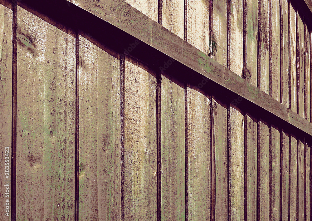 A wooden fence with vertical panels and horizontal cross bar in closeup ...
