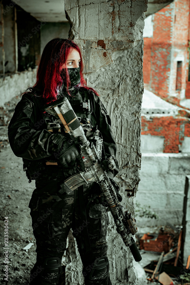 Airsoft red-head woman in uniform and put down machine gun. Close up ...