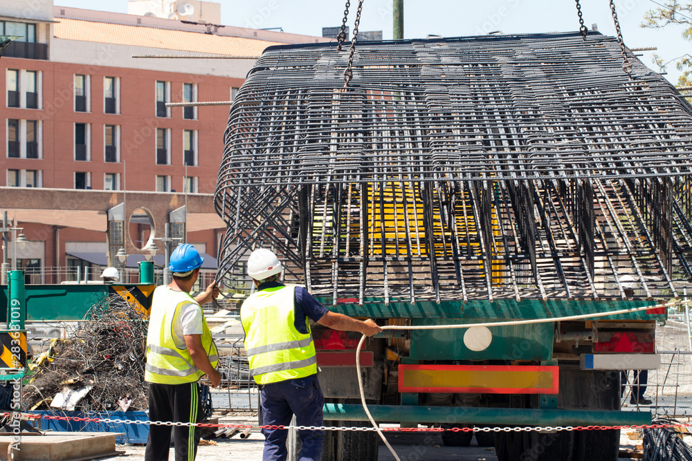 Steel rebars. Construction worker unload from the truck a part of ...