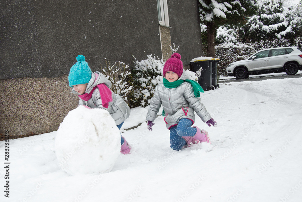 little children roll a big snowball, build a snowman in the winter ...