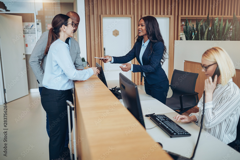 Friendly concierge helping two guests check in to a hotel Stock Photo ...