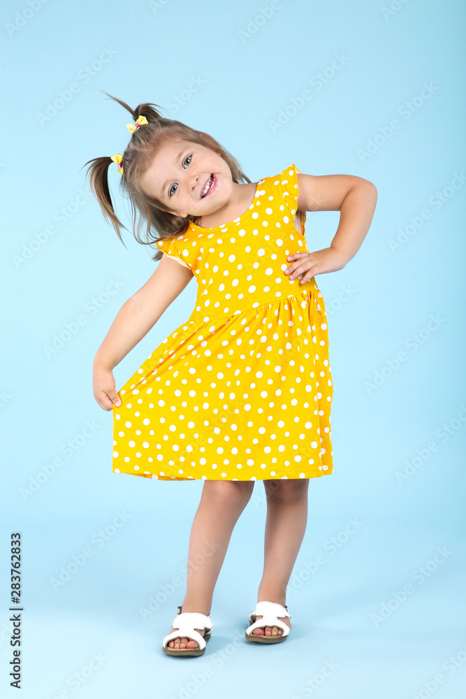 Cute little girl in yellow dress on blue background Stock Photo | Adobe ...