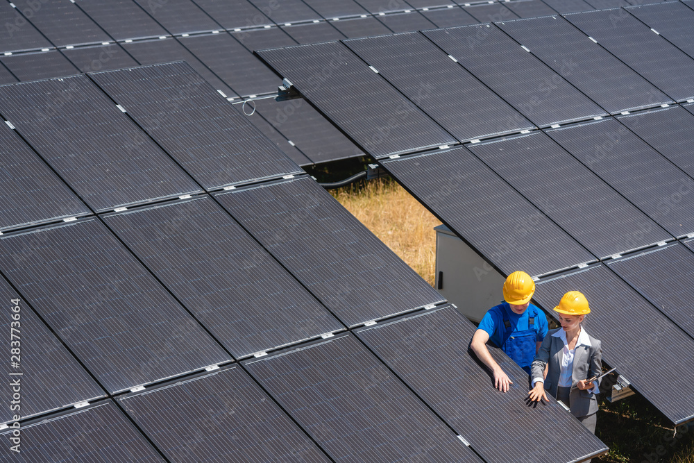 Two people standing amid solar cells in a power plant Stock Photo ...