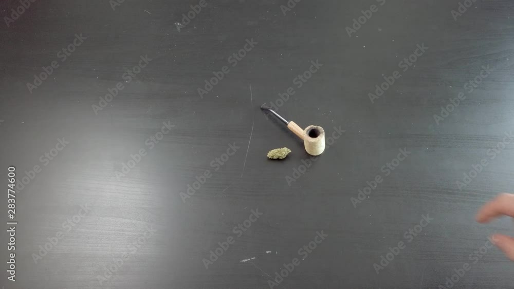 White male model hand placing weed pipe and marijuana buds on a solid ...