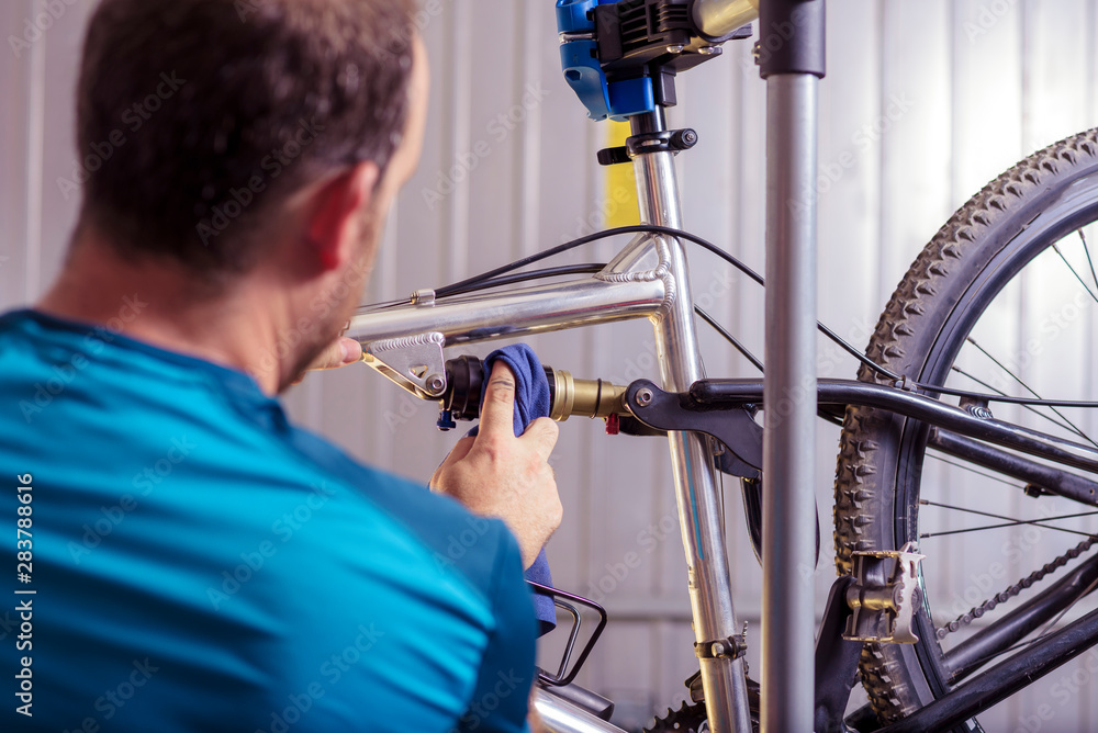 Mechanic in a bicycle repair shop oiling the chain of a bike. Man ...