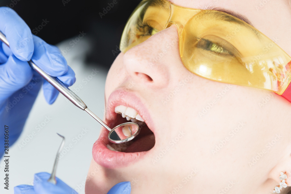 A close-up of the girl's face is examined by a dental examiner with his ...