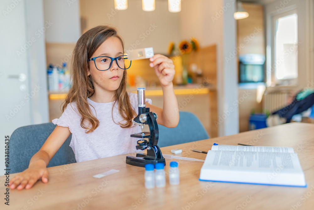 Confident little girl uses microscope at home. Beautiful elementary ...