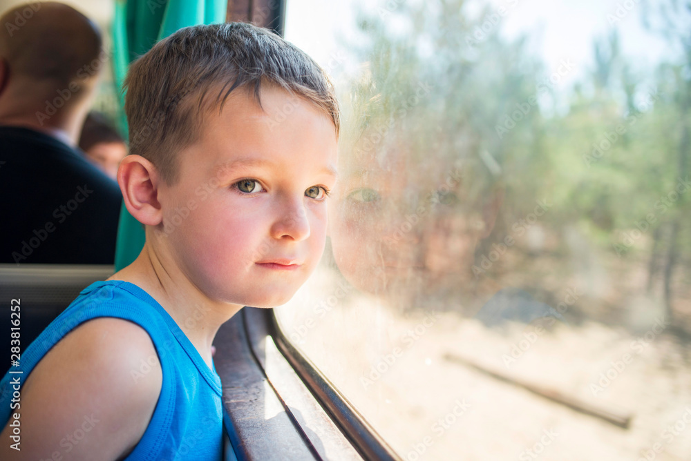 The boy is traveling by train and looks out the window, watching the ...