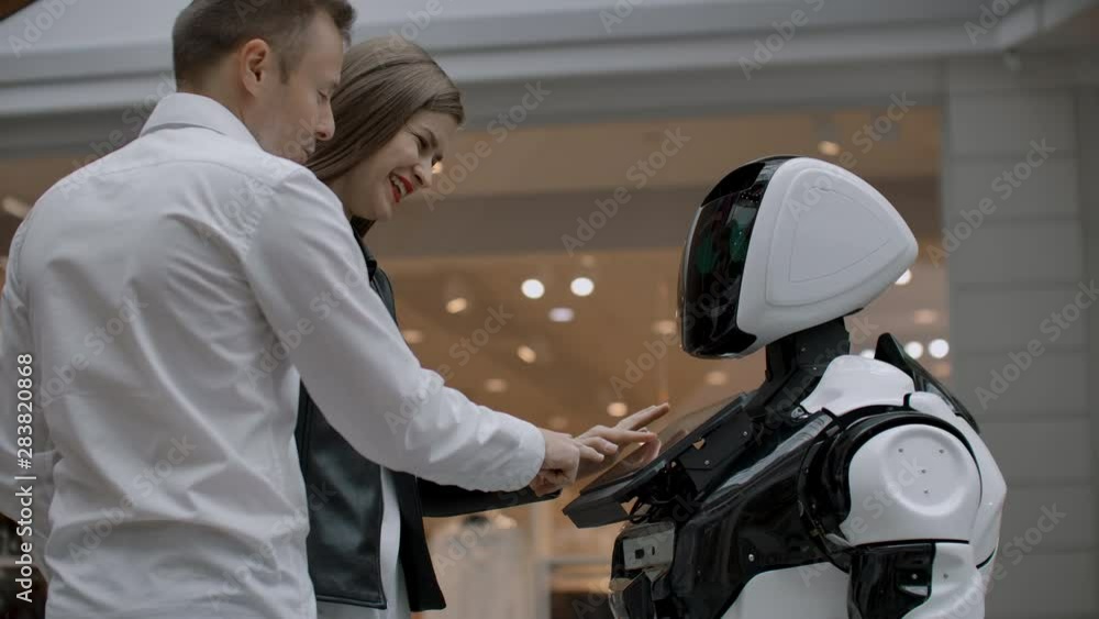 Two people a man and a woman communicate with a robot. Press the robot ...