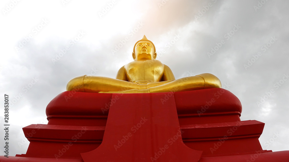 Statue of Luang Pho Sothon A large golden body on a red base on the sky ...