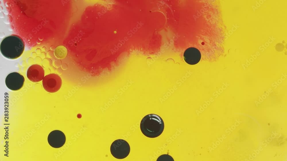 black and red dots are floating in a bright yellow and red liquid ...