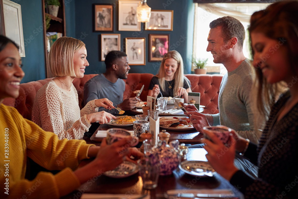 Group Of People Eating In Restaurant Of Busy Traditional English Pub ...