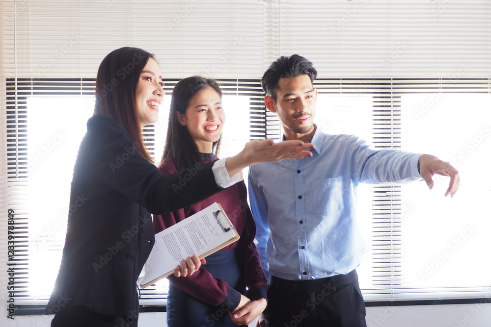 Agent talking happily with customers in the office pointing at ...