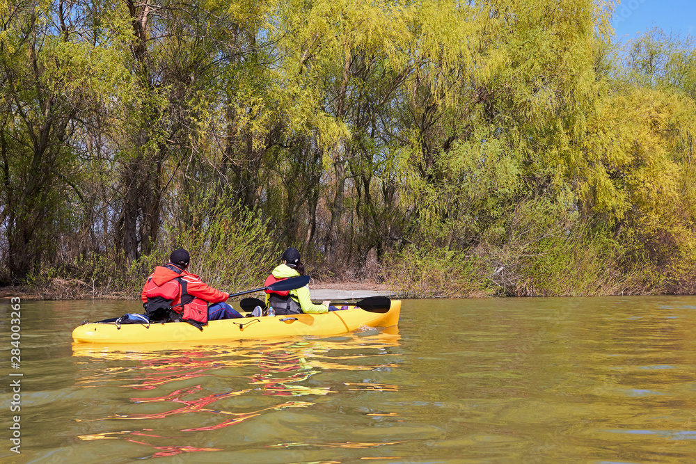 Сouple (man and woman) paddle a yellow kayak in at Danube river among ...