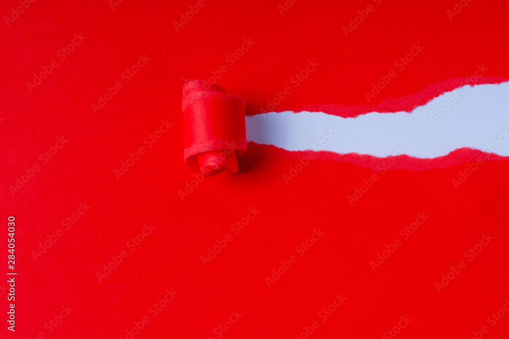 Torn red coloured paper on white background with closeup hole in the ...