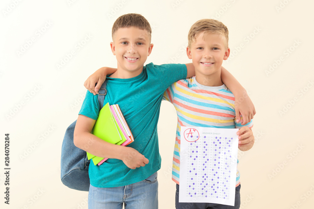 Happy boys with answer sheet for school test on light background Stock ...