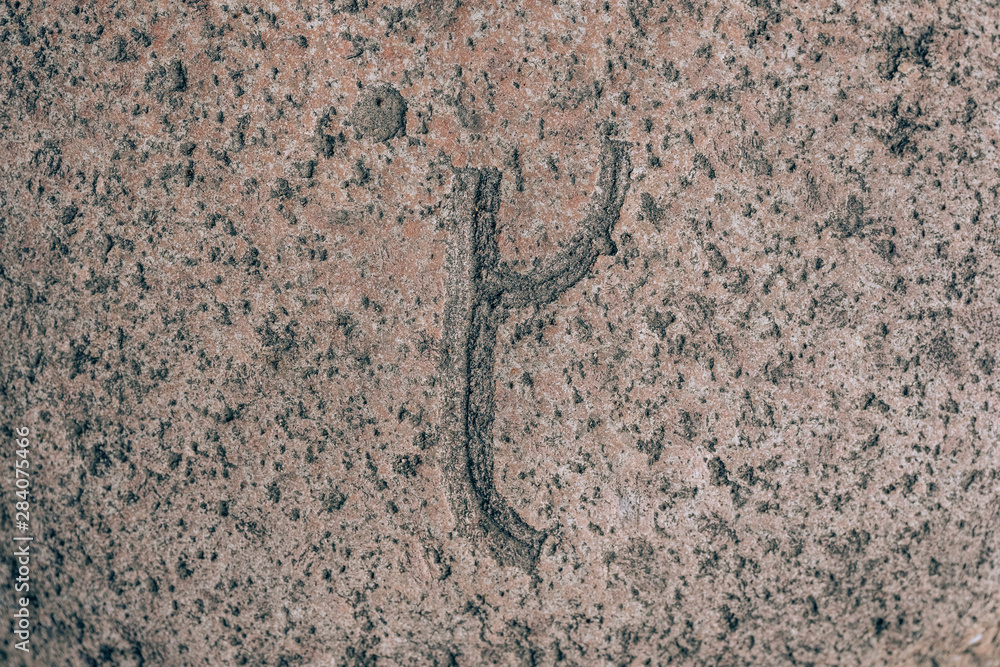 A sign carved on a stone. Letter of the alphabet on granite. Stone ...