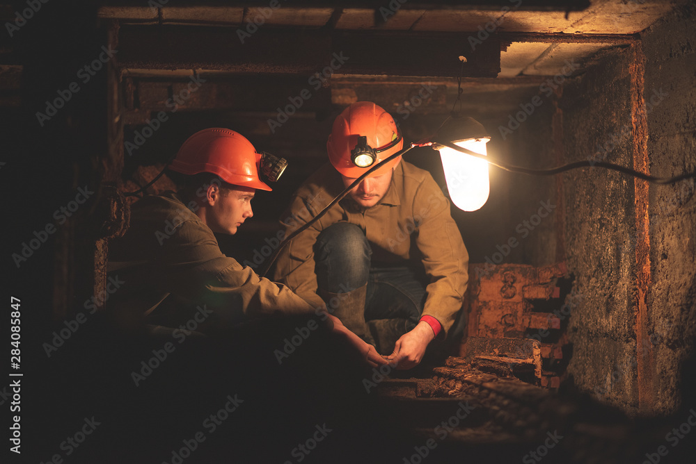 Two young guys in a working uniform and protective helmets, sitting in ...