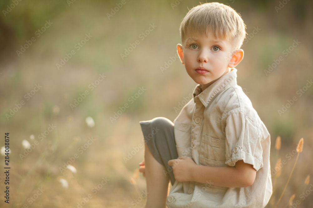 Cute, naive, little, blonde baby boy is sitting admiring nature. Close ...