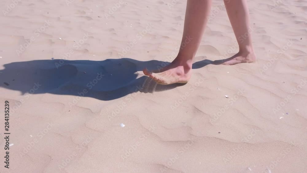 Barefooted girl traveller go by seashore on hot sand. Woman tourist ...