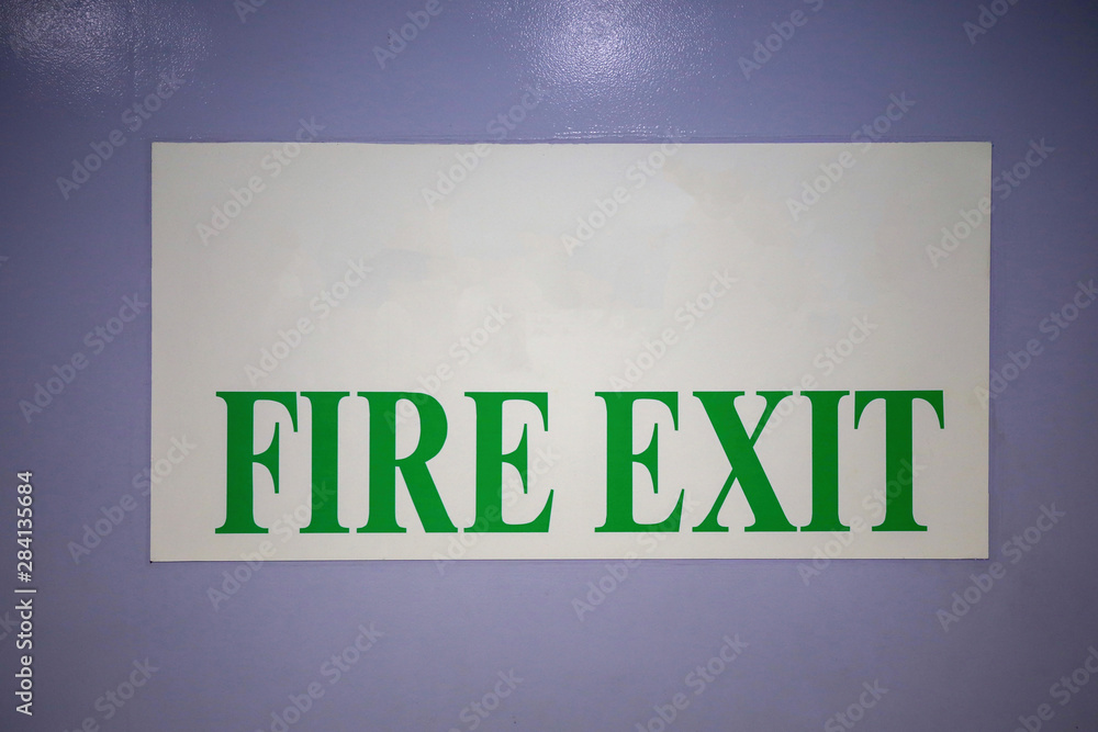 The green warning sign on white background label is "FIRE EXIT". Stock ...