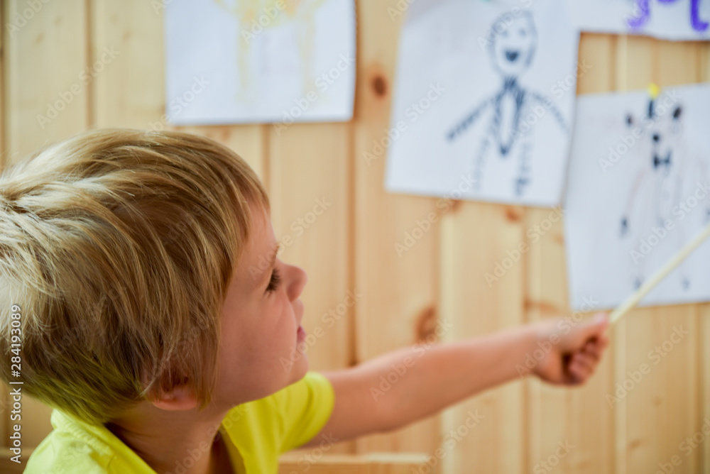 The child talks about his drawings. Pictures are fixed on the wall. The ...
