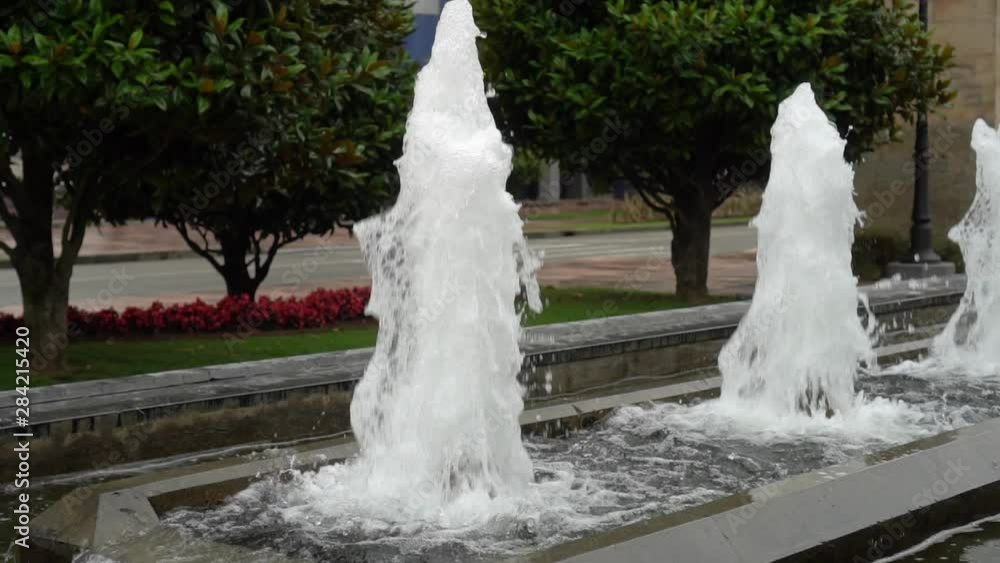 Foamy streams of water rise and fall. Alley of fountains in a city park ...