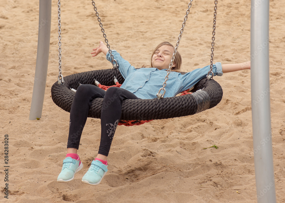 Happy teen girl on swing in playground outdoors. Beautiful student ...