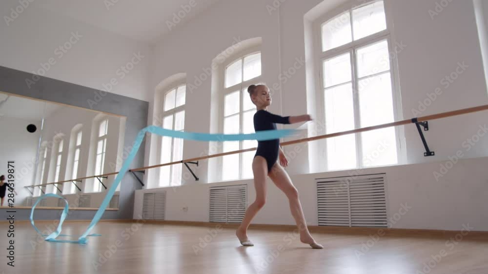 Wide shot of Caucasian female acrobat wearing black leotard exercising ...