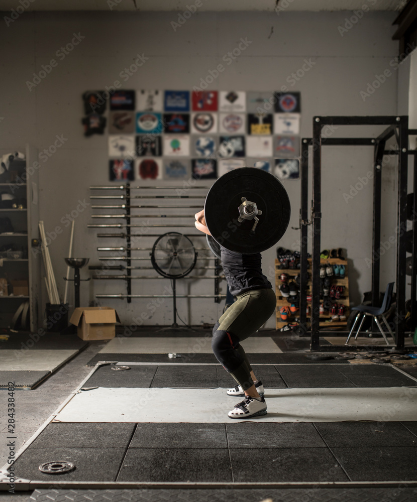 Female power lifter lifting heavy weights in dark gym, anonymous ...