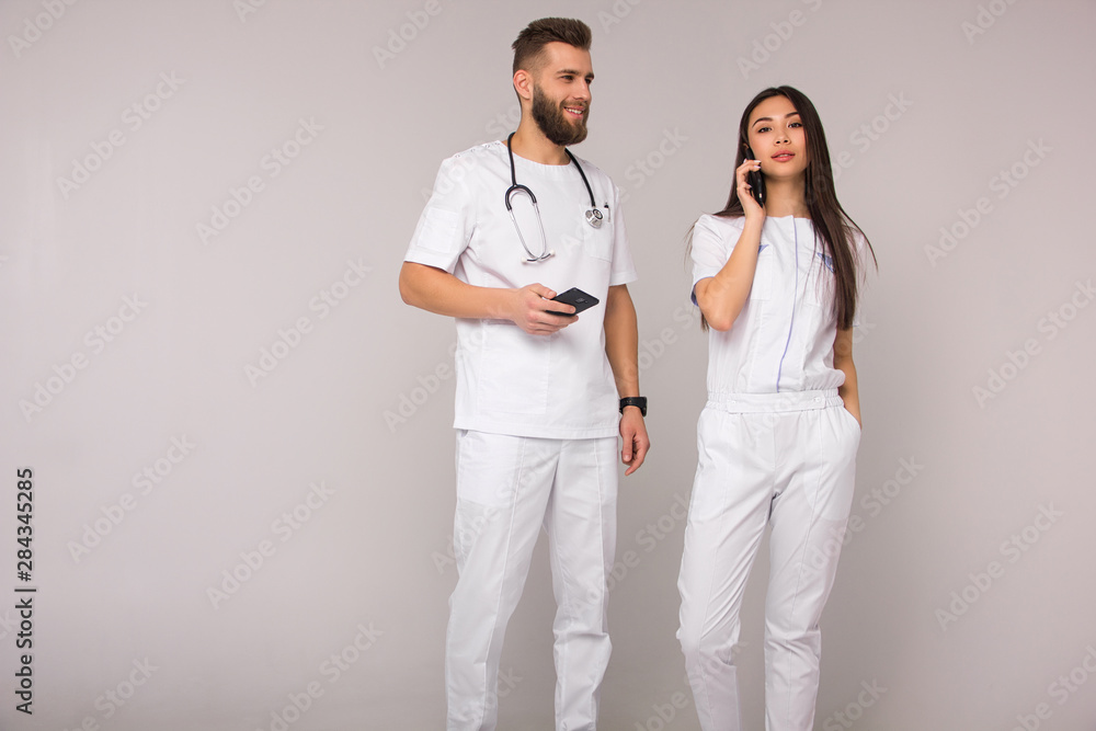 two young stylish doctors, male and female nurses, in white casual ...