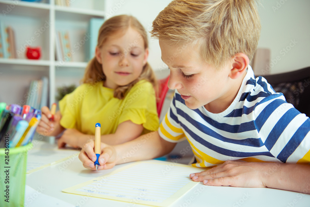 Cute schoolchildren are came back to school and learning at the table ...