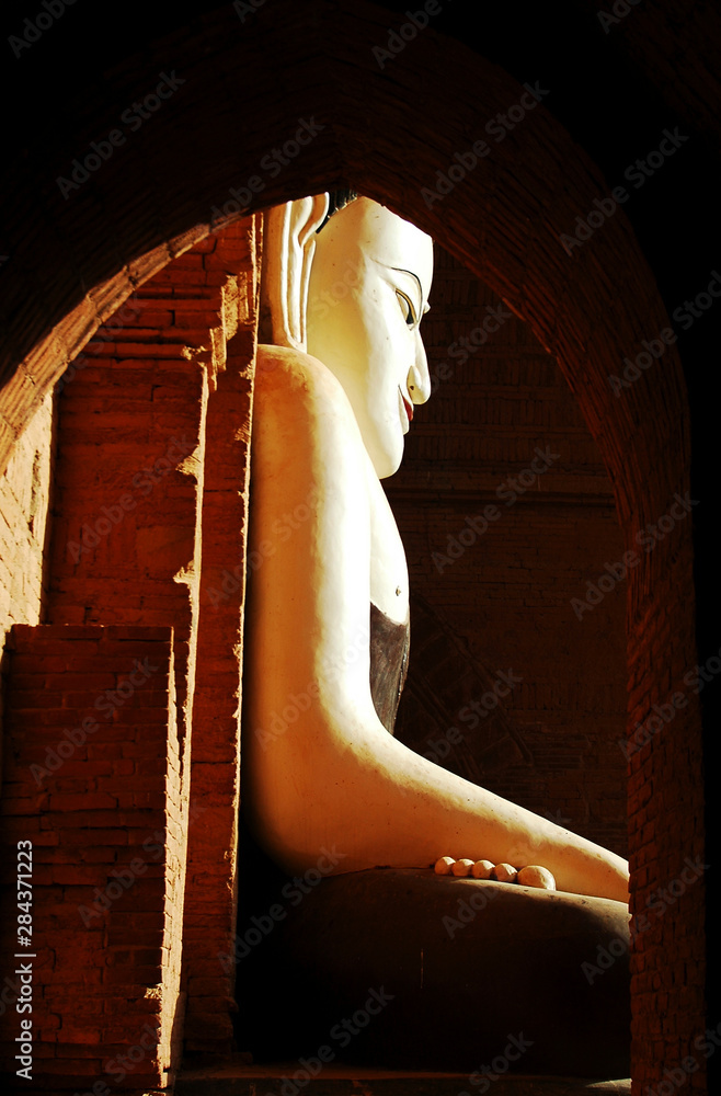 Myanmar, Bagan, profile of statue of a sitting Bhudda in his red dress ...