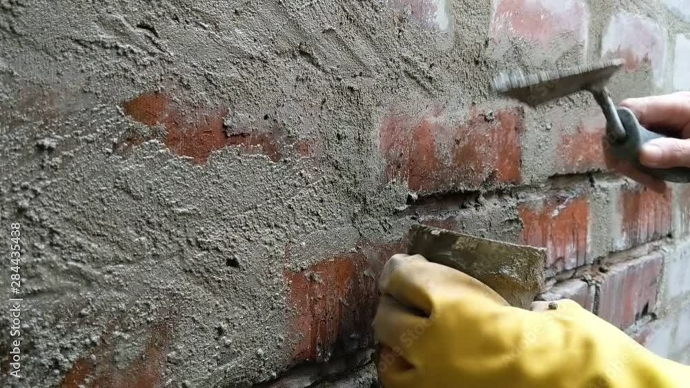 Woman pointing joints of old red brick garden wall. Closeup of hands ...