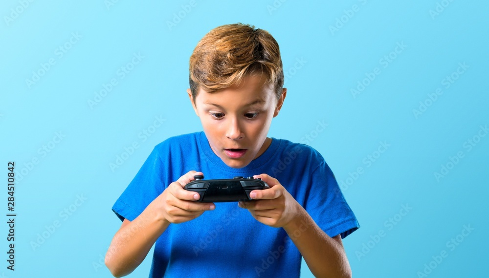Kid playing the console on blue background Stock Photo | Adobe Stock