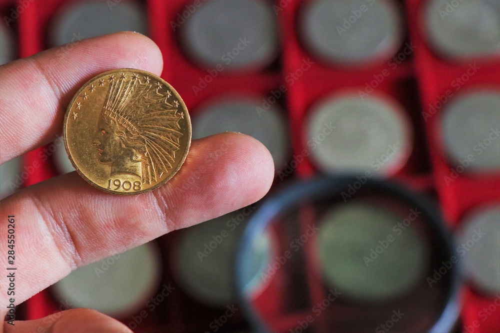 Numismatic at work shows some gold coins. Detailed view of an Indian ...
