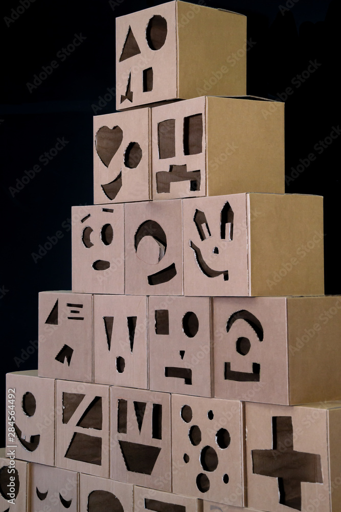 Pyramid from boxes with cuts in the form of funny persons on a black ...
