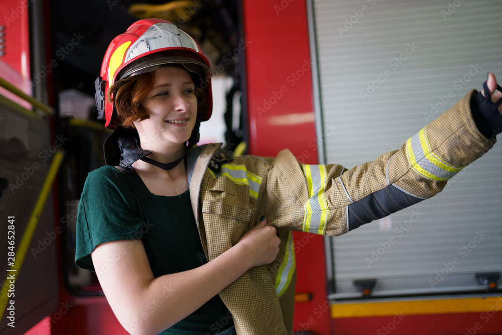 Photo of woman in helmet putting on work clothes in fire truck Stock ...