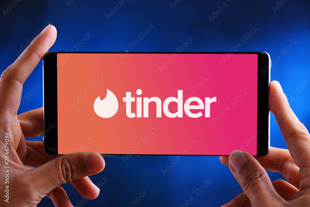 Hands holding smartphone displaying logo of Tinder Stock Photo | Adobe ...
