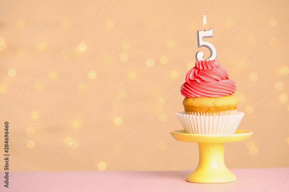 Birthday cupcake with number five candle on stand against festive ...