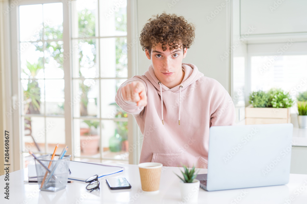 Young student man working and studying using computer laptop pointing ...