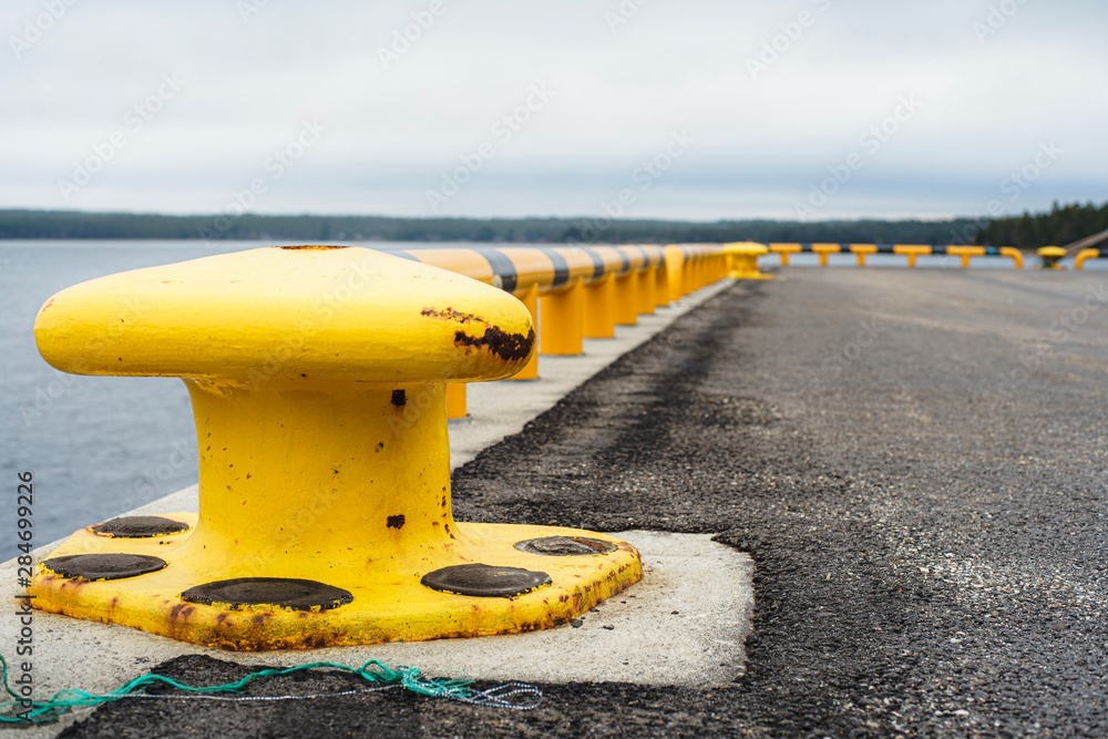 Close-up of yellow metallic mooring column or bollard on the edge of ...