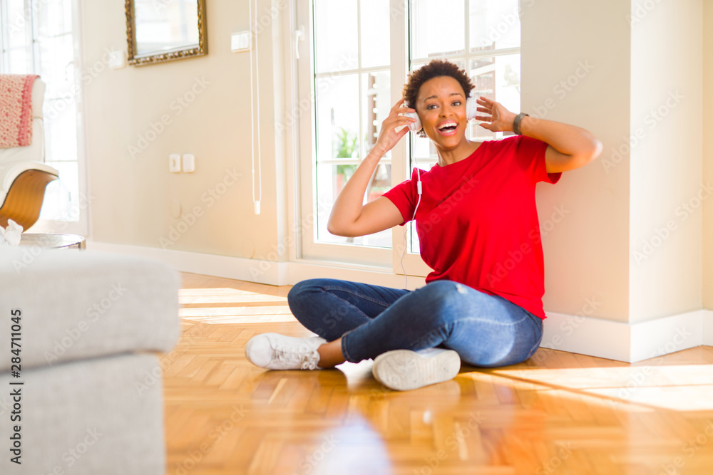 Beautiful young african american woman with afro hair listening to ...