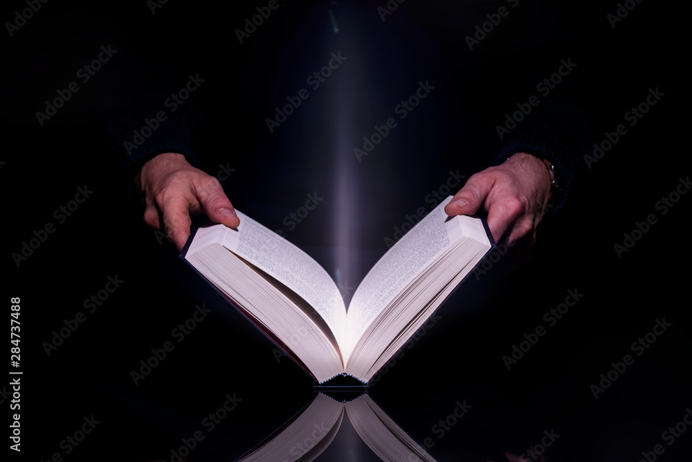 Person reading book with glowing light coming from inside of it. High ...