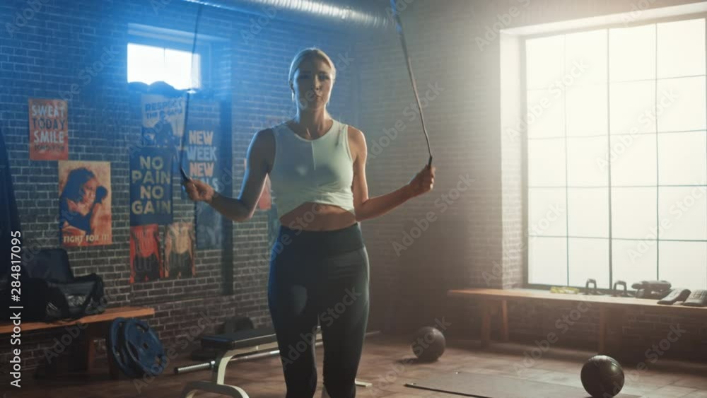 Fit Athletic Blond Woman Exercises with Jumping Rope in a Loft Style Industrial Gym. She Does ...