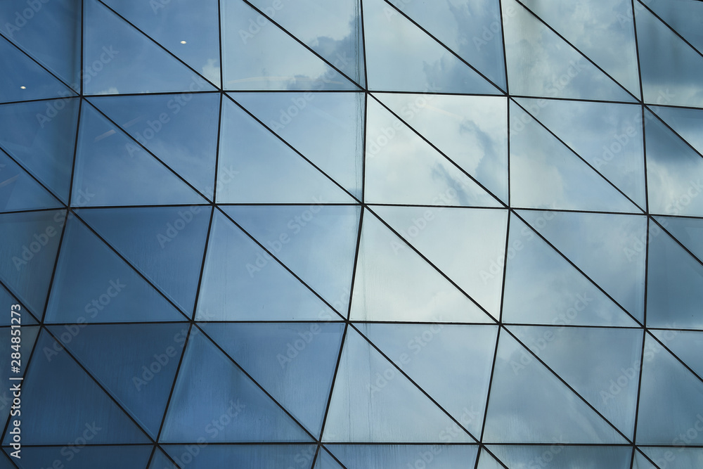 Abstract square and triangle pattern design glass facade wall or window with sky reflection ...